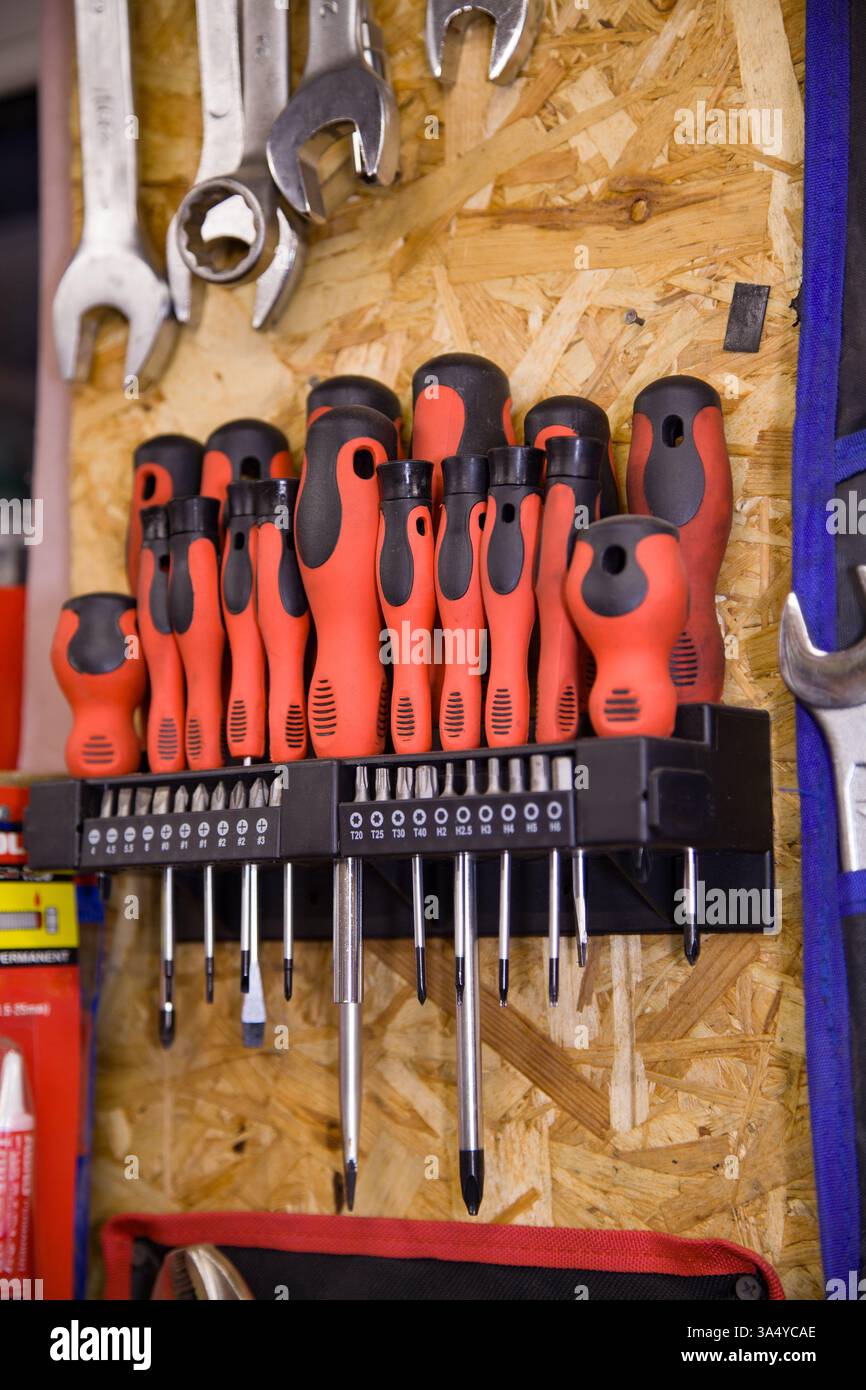 A set of various screwdrivers with red rubber handles is hanging on a ...