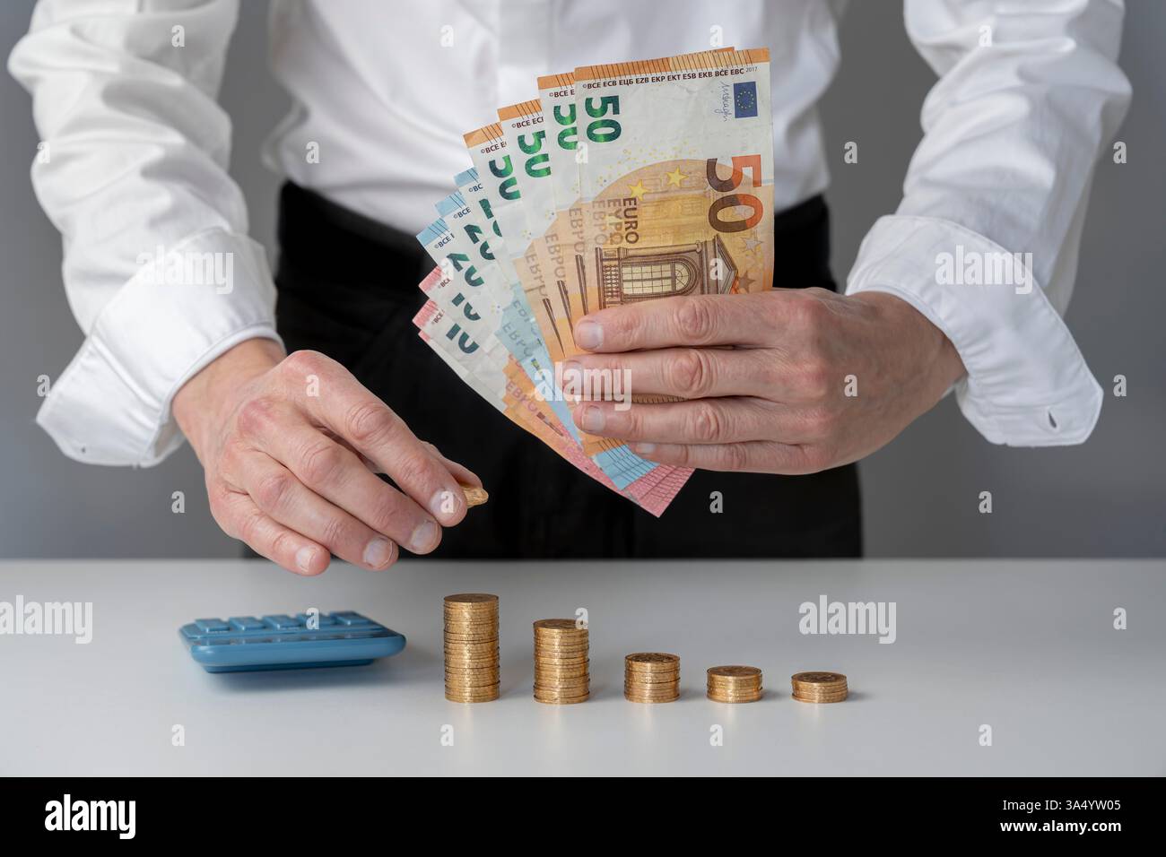 Close-up view man's hand putting a gold coin on a stack of gold coins ...