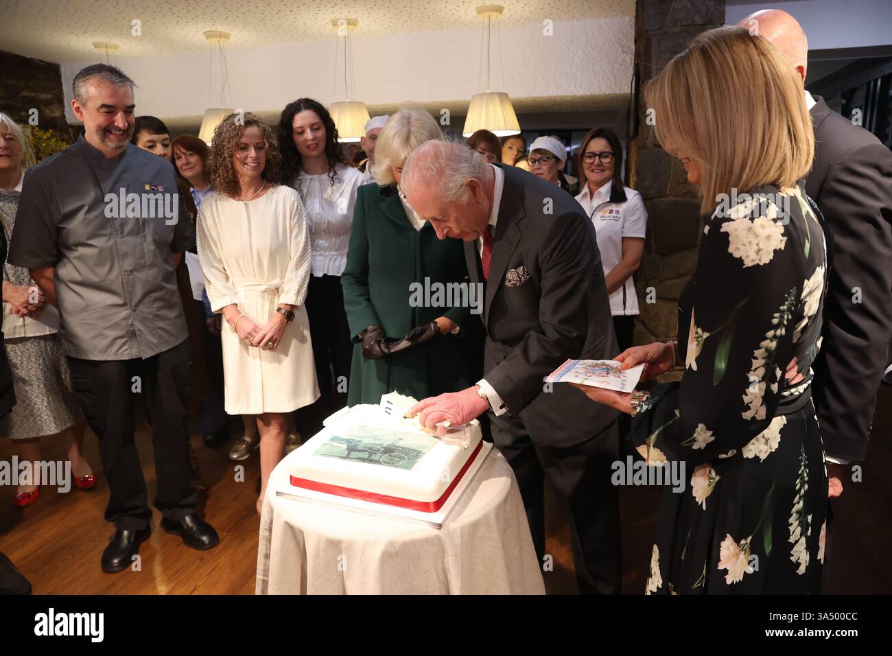 King Charles III tastes a cake he cut into at Hunters Bakery in ...