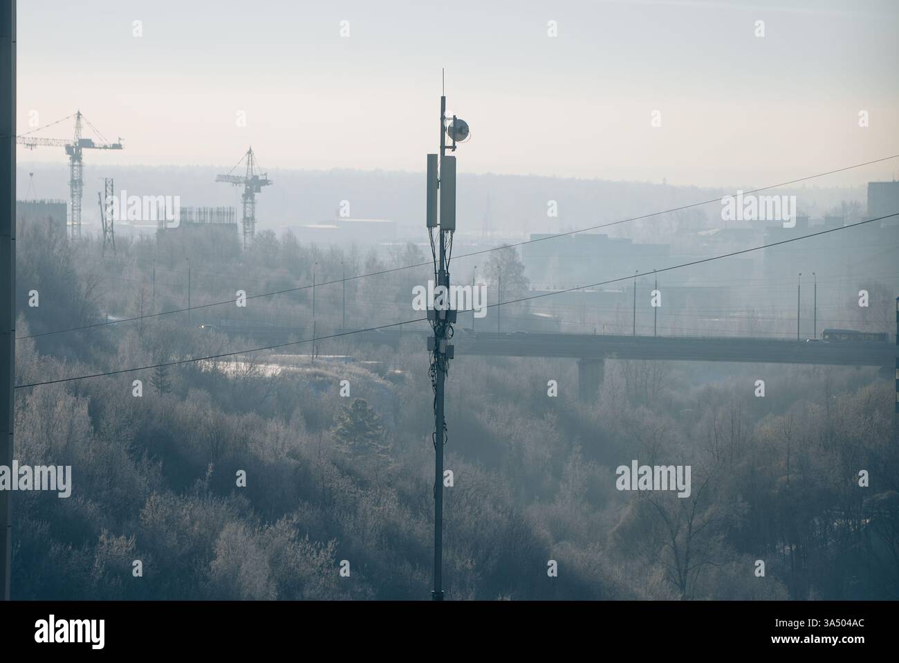 Telecommunication tower rising amidst a foggy industrial landscape ...