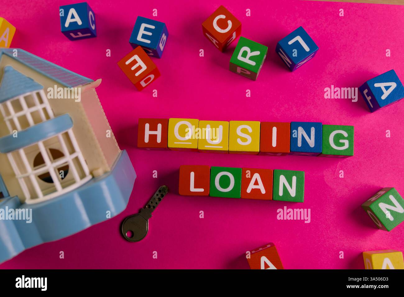 Blocks spelling housing loan surround a house model and key on a bright ...