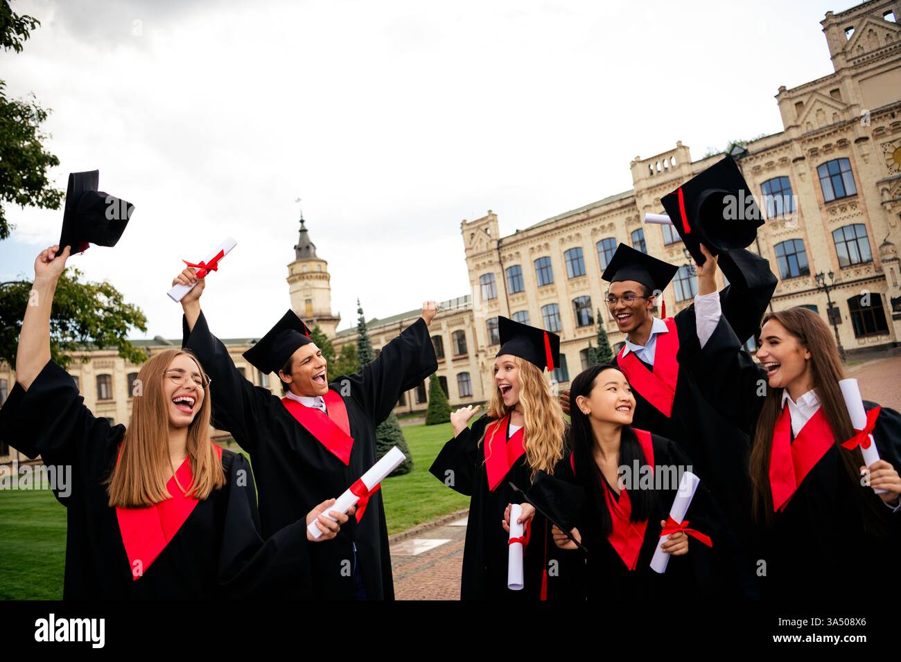 Joyful university students celebrate graduation outdoors in summer ...