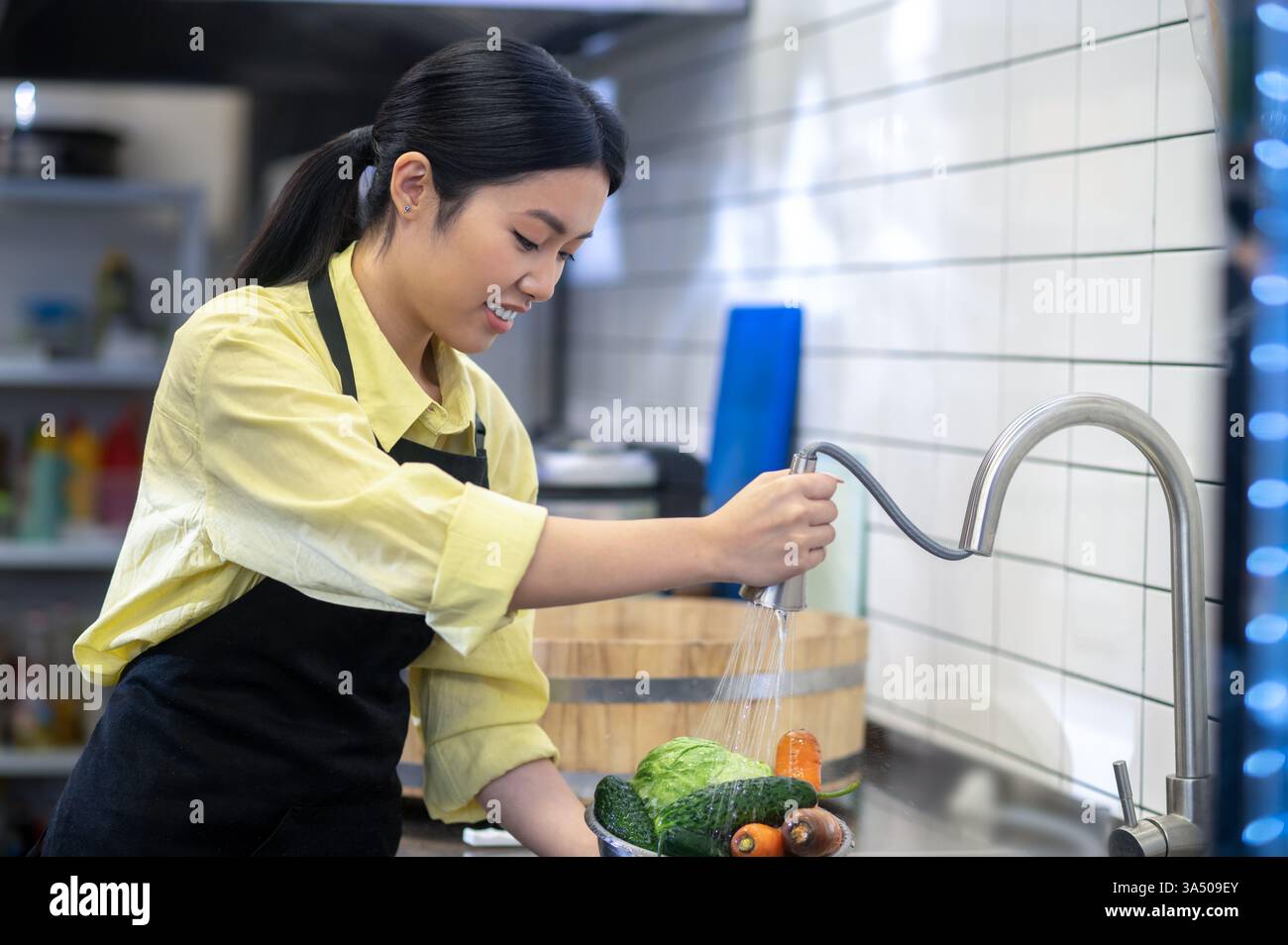 Preparation. Woman in the kitchen washing vegetables before cooking ...
