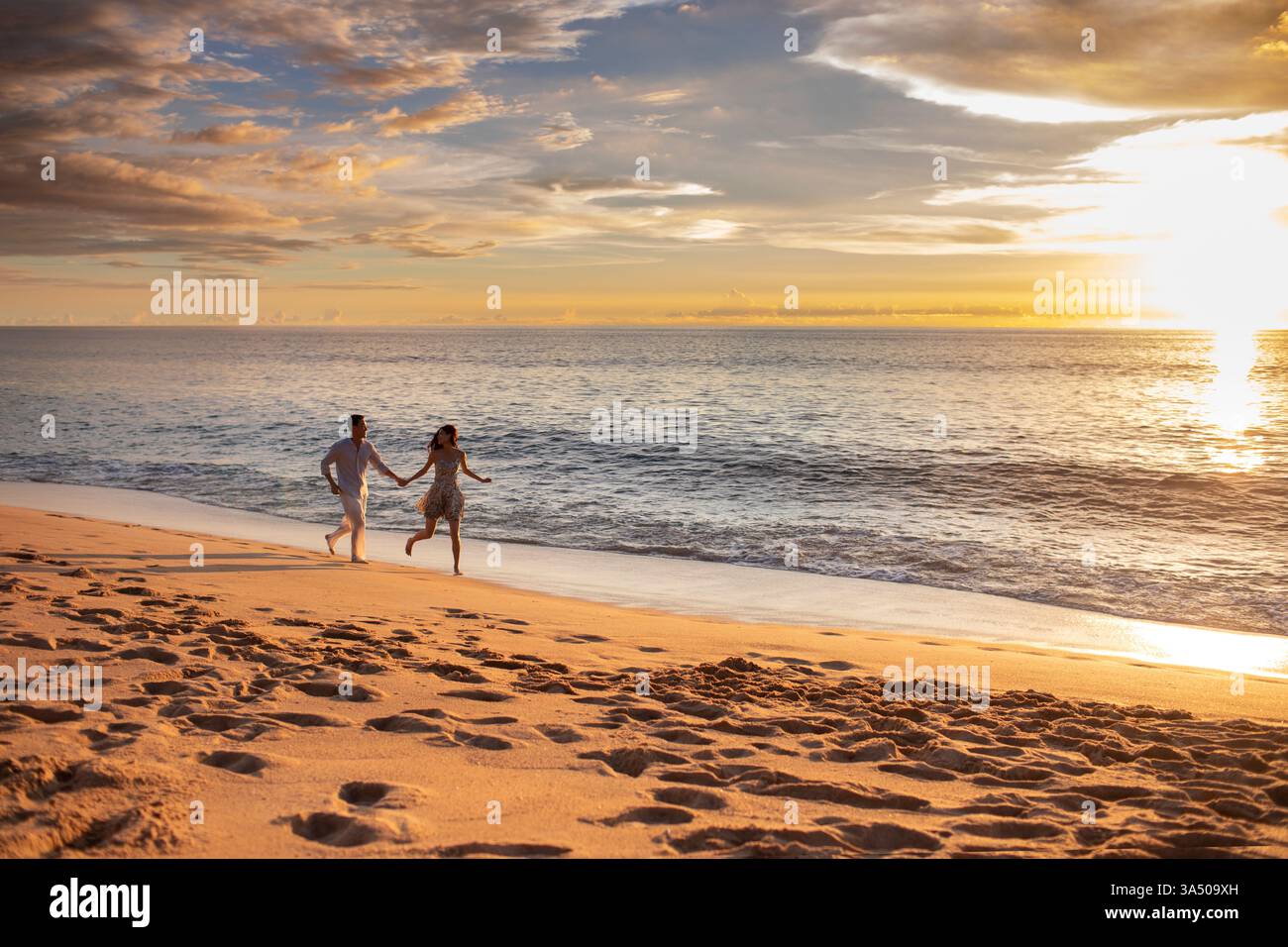 Cheerful Chinese couple running on beach during sunset Stock Photo - Alamy
