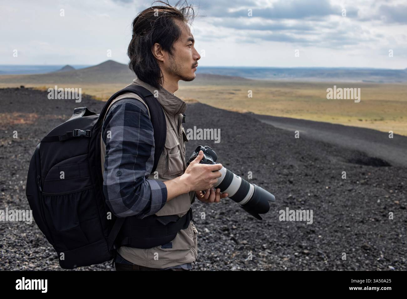 Chinese male photographer looking at a view during a hiking trip ...