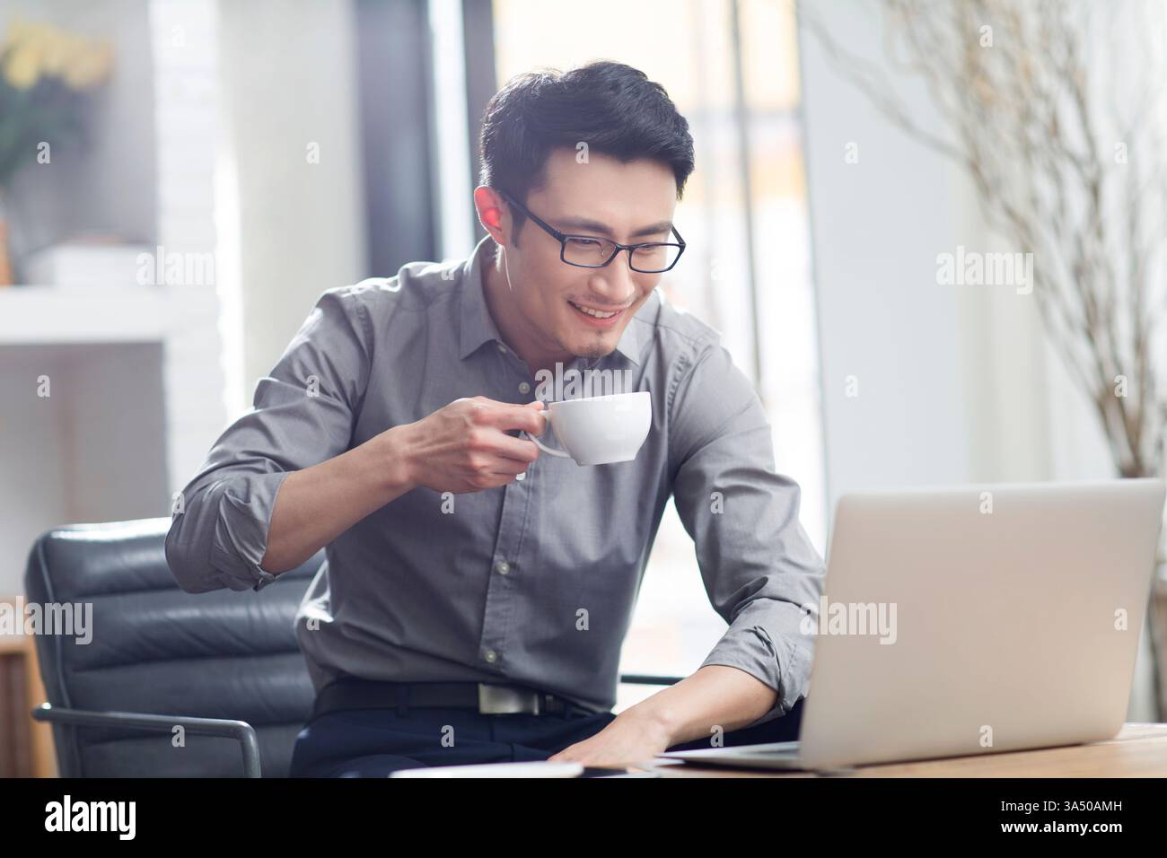 Young Chinese man working with laptop in office Stock Photo - Alamy