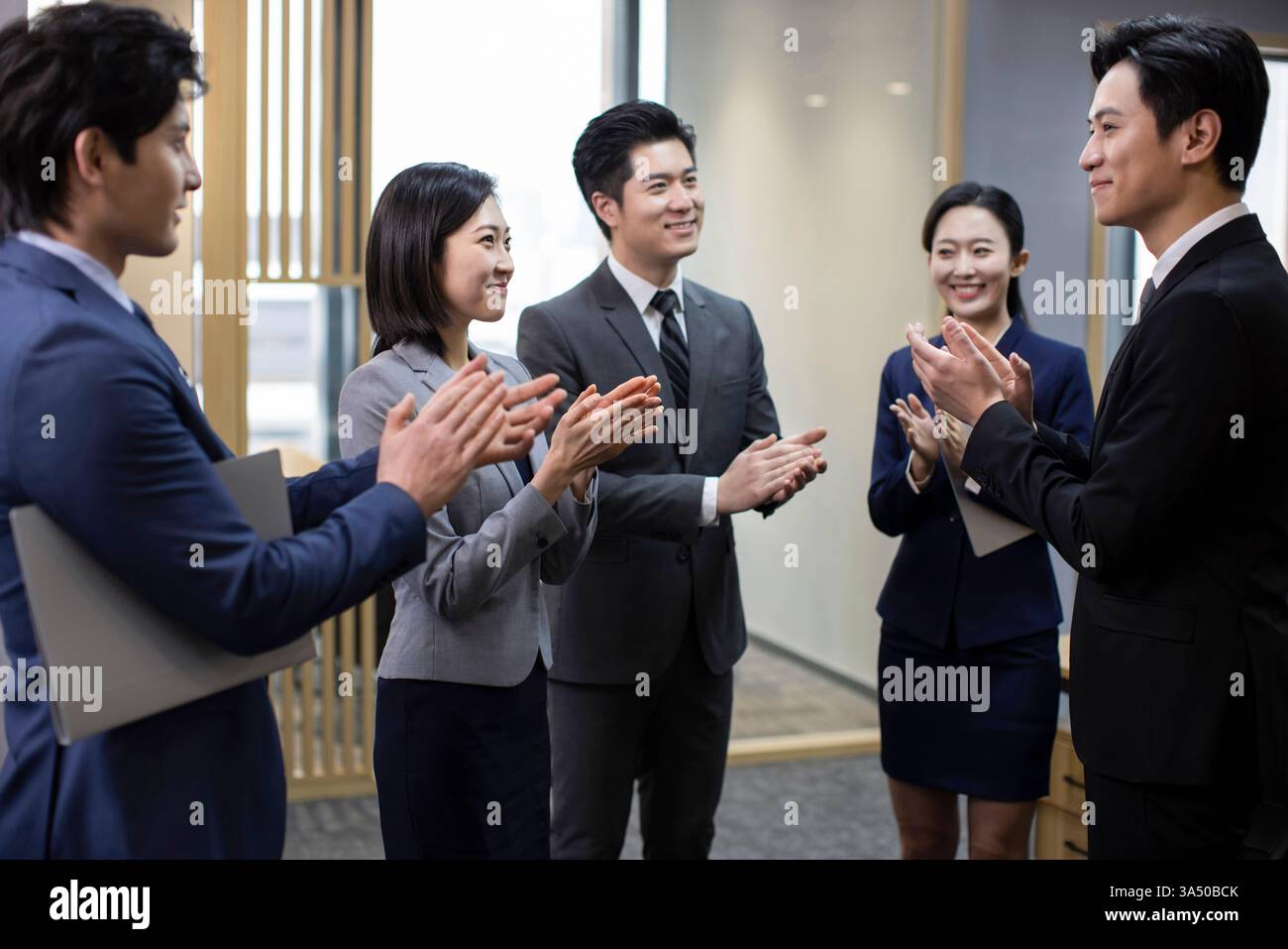 Cheerful Chinese business people standing applauding after meeting in ...