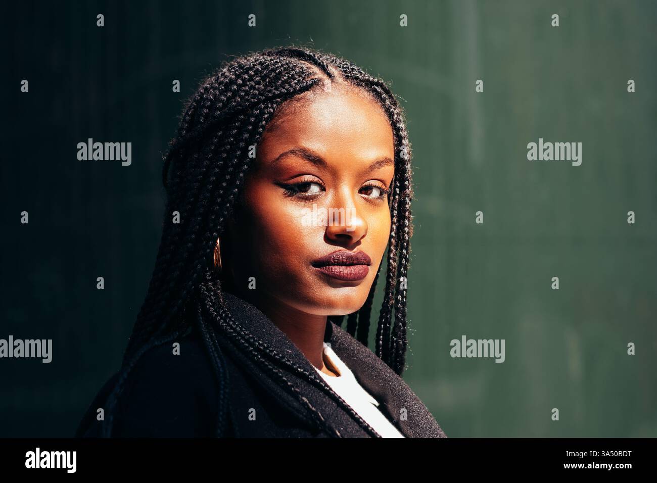 Serious Black woman with long braids wearing black suit standing ...