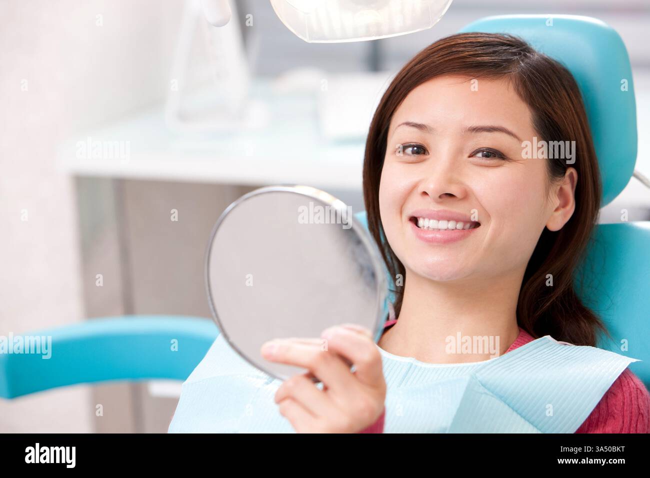 Chinese patient examining teeth in mirror Stock Photo - Alamy