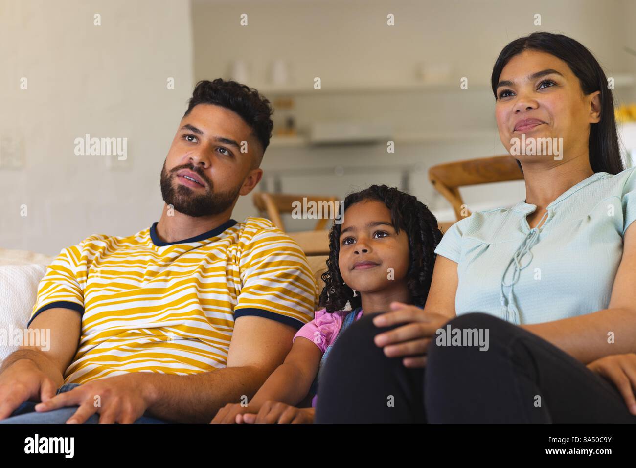 Family watching TV together at home, enjoying quality time on couch ...