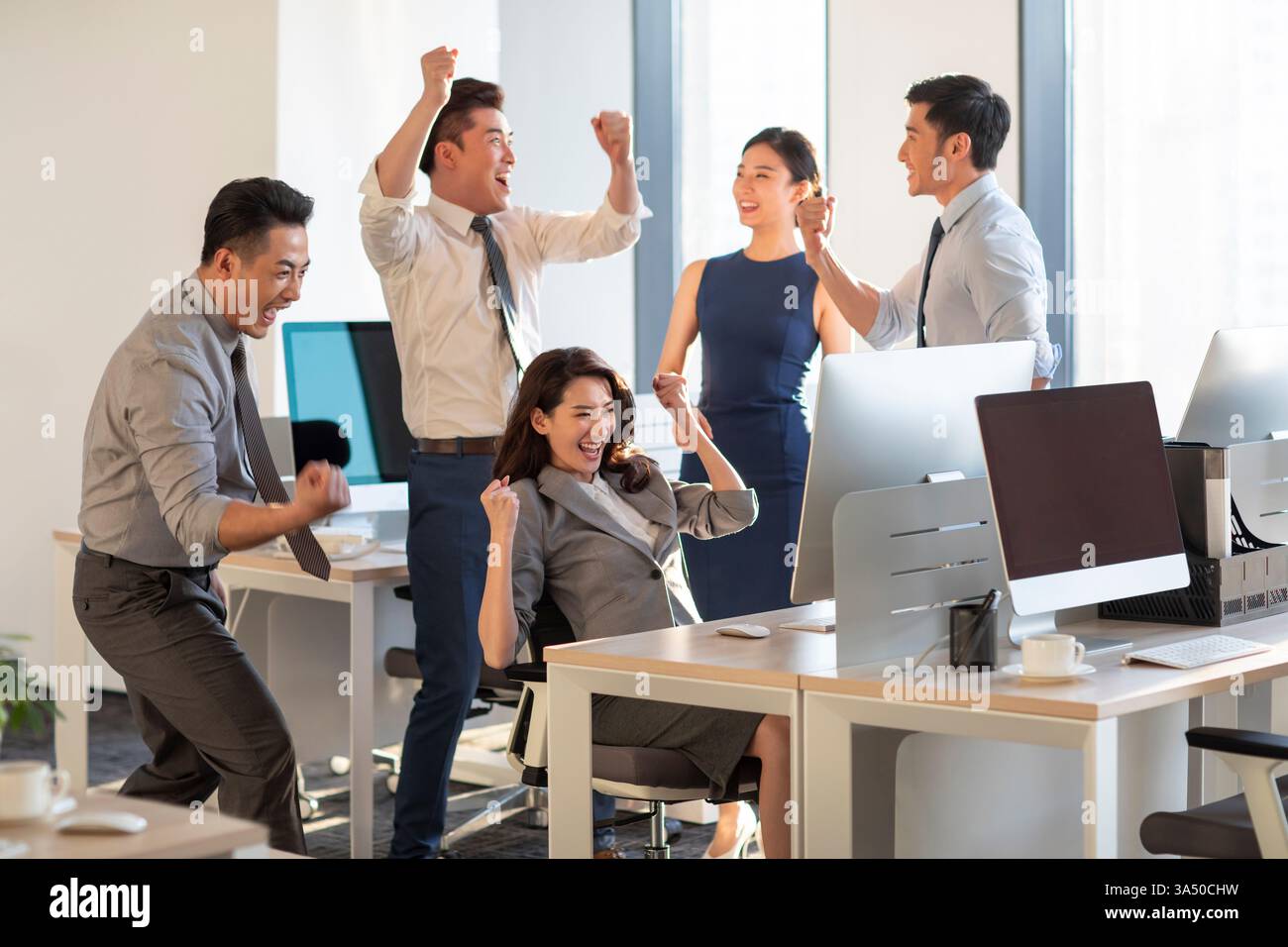 Cheerful Chinese business people celebrating while working together in ...