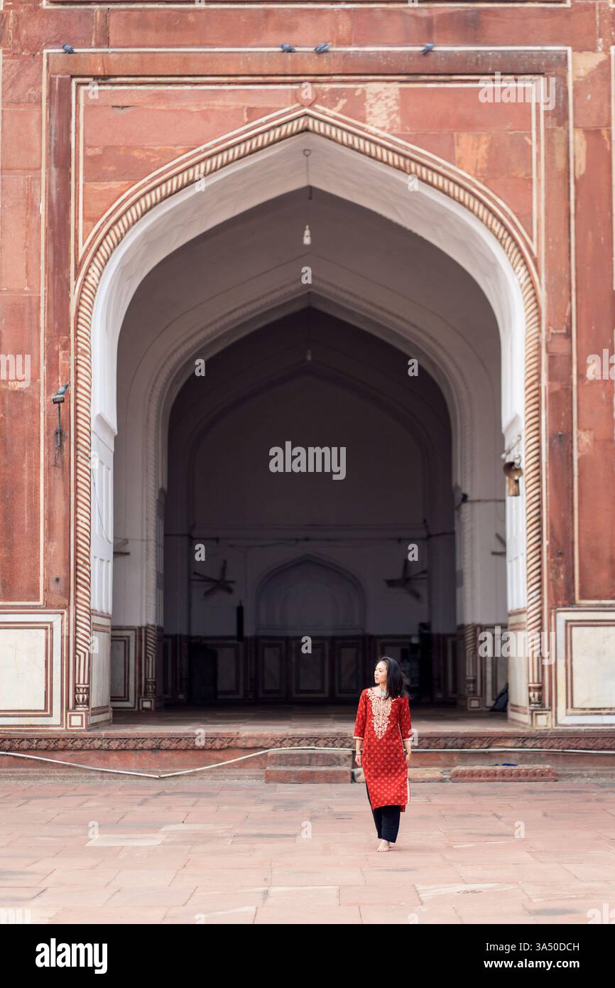 Asian female tourist in red traditional dress looking away walking ...
