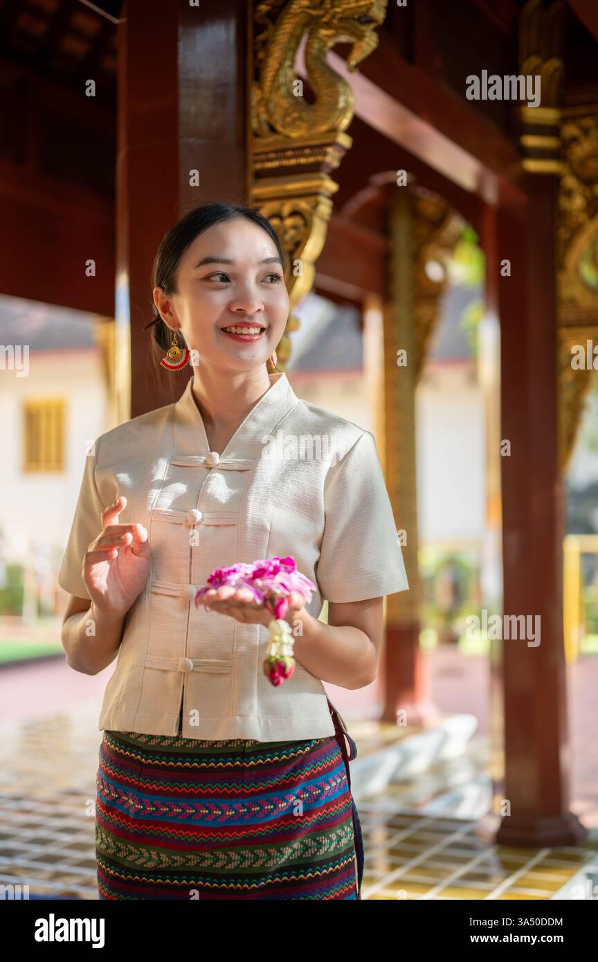 A charming and beautiful Asian Thai woman in a traditional Thai-Lanna dress with a beautiful ...