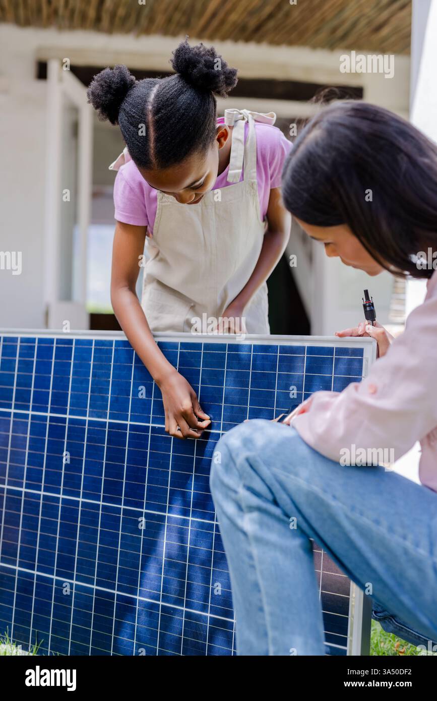 Installing solar panel outdoors, child and woman learning about ...