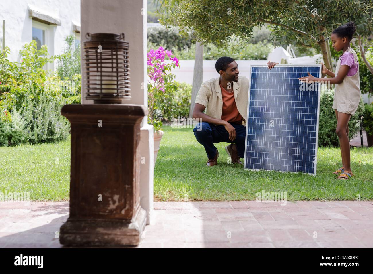 Father and daughter installing solar panel in garden, enjoying sunny ...