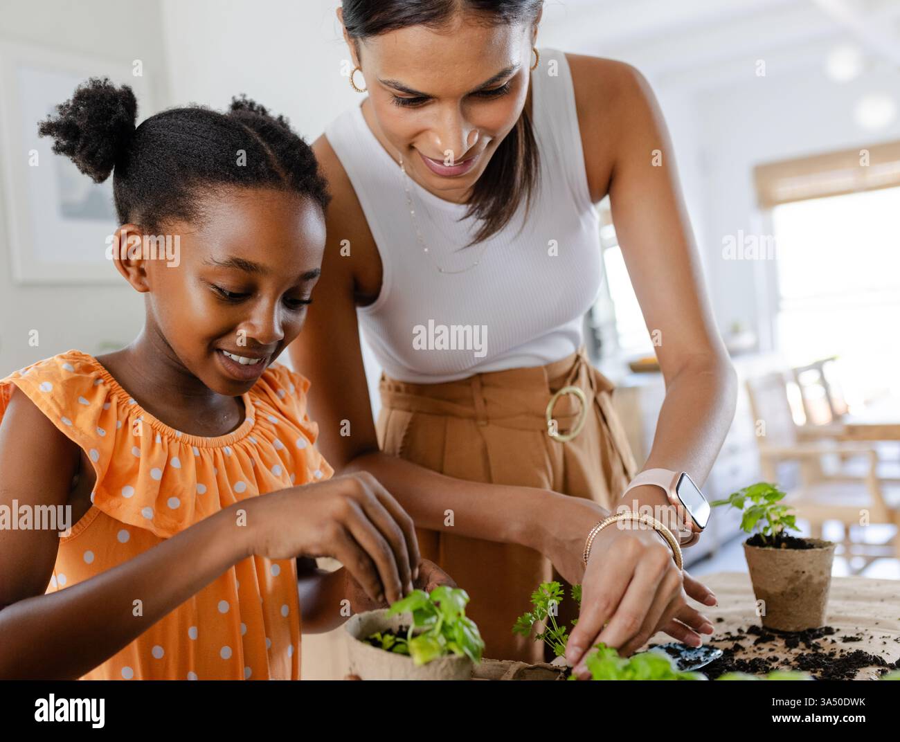 Mother and daughter planting herbs together at home, enjoying quality ...