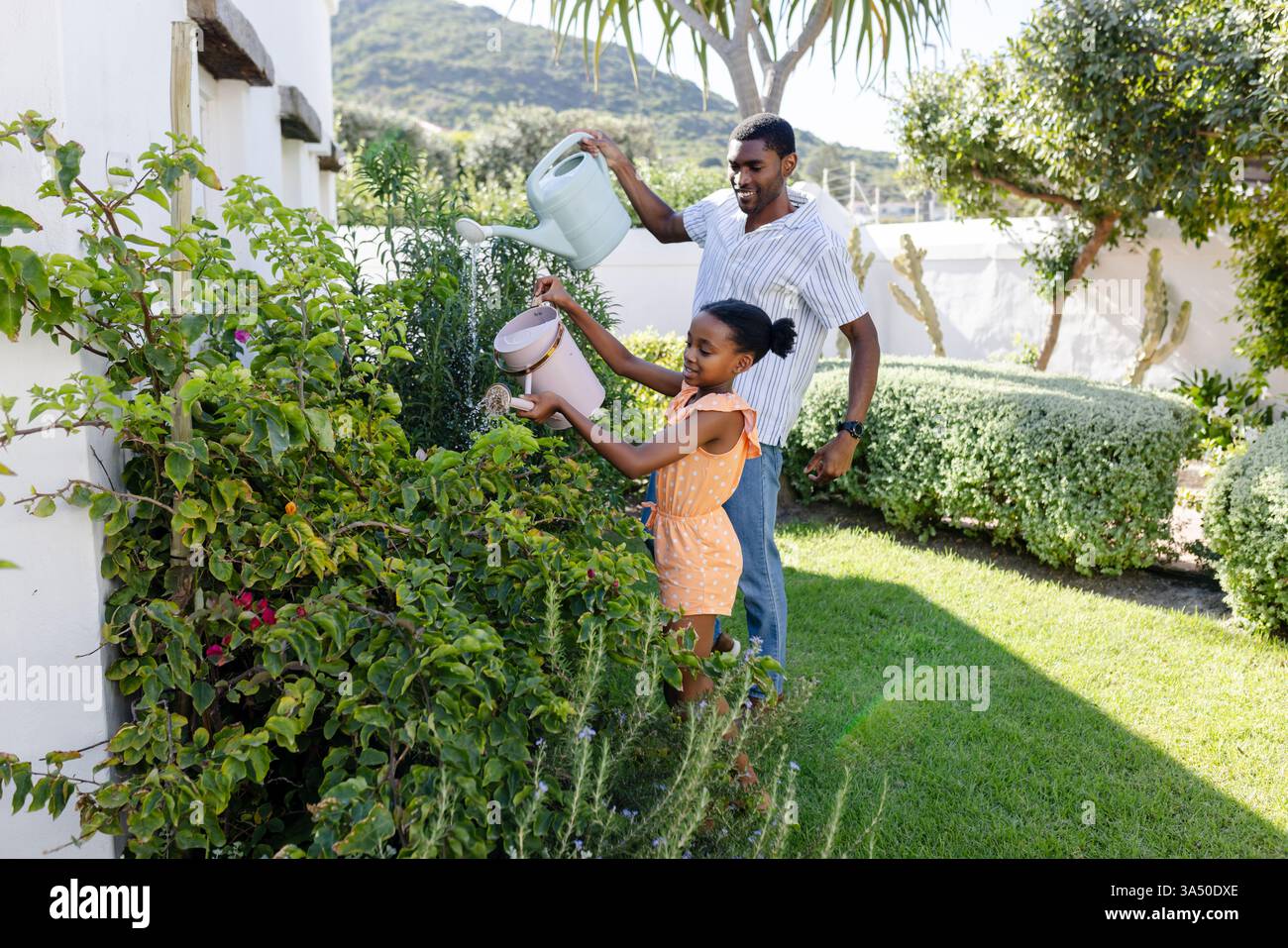 Father and daughter watering garden plants together, enjoying outdoor ...