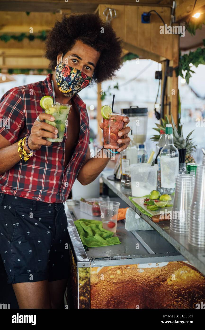 African American bartender outdoors wearing a face mask, holding ...