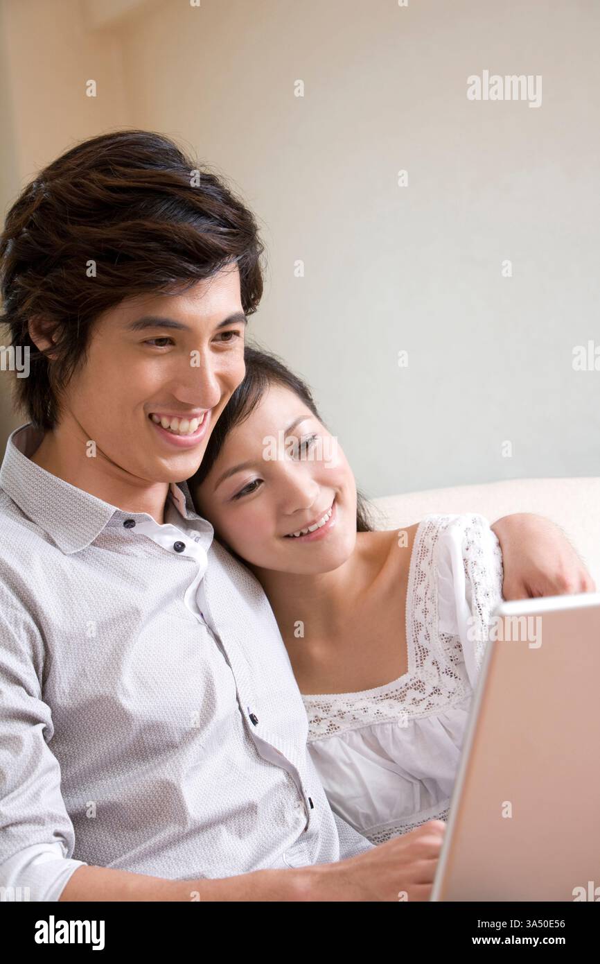 Chinese couple cuddling on a sofa Stock Photo - Alamy