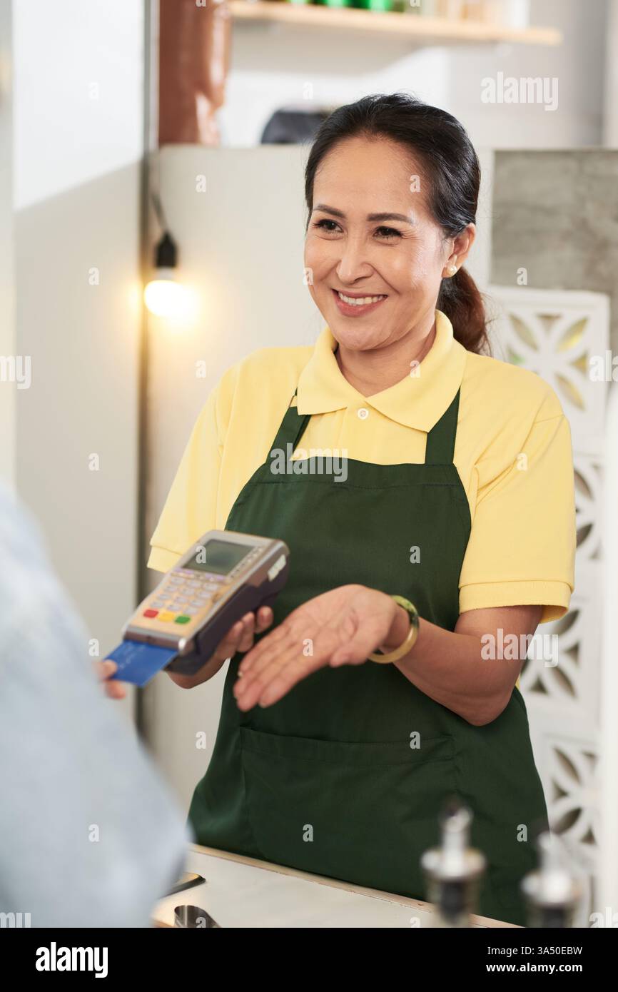 Asian woman giving card reader to customer for payment in cafe Stock ...