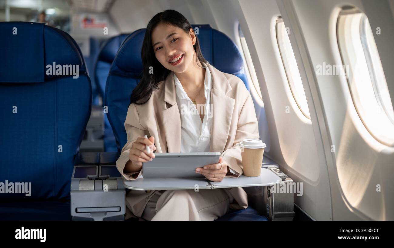 Smiling Asian business woman holding stylus pen and tablet sitting with ...
