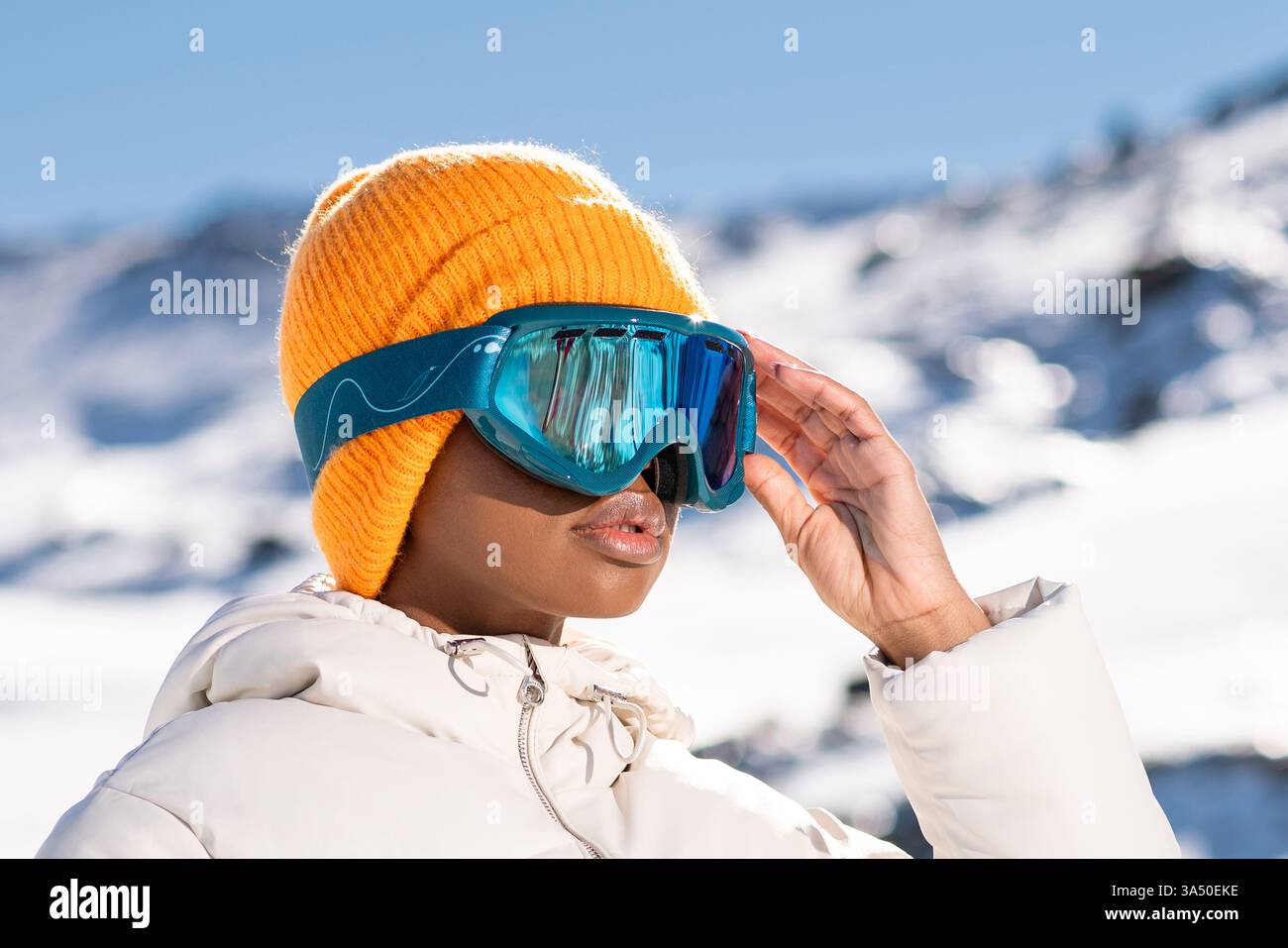 African American woman touching ski goggles in a snowy mountain ...