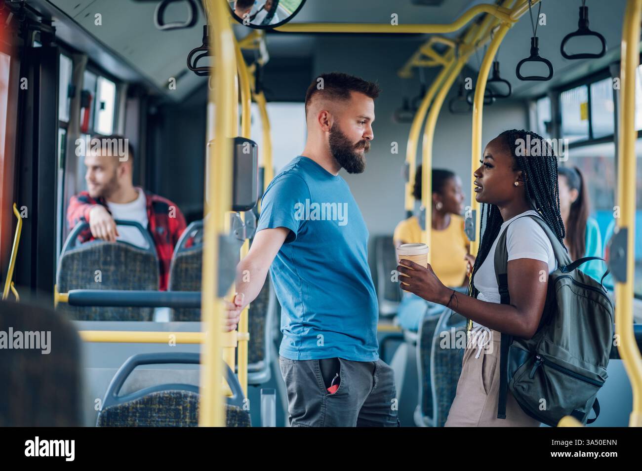 Multiracial friends talking while standing together in city bus and ...