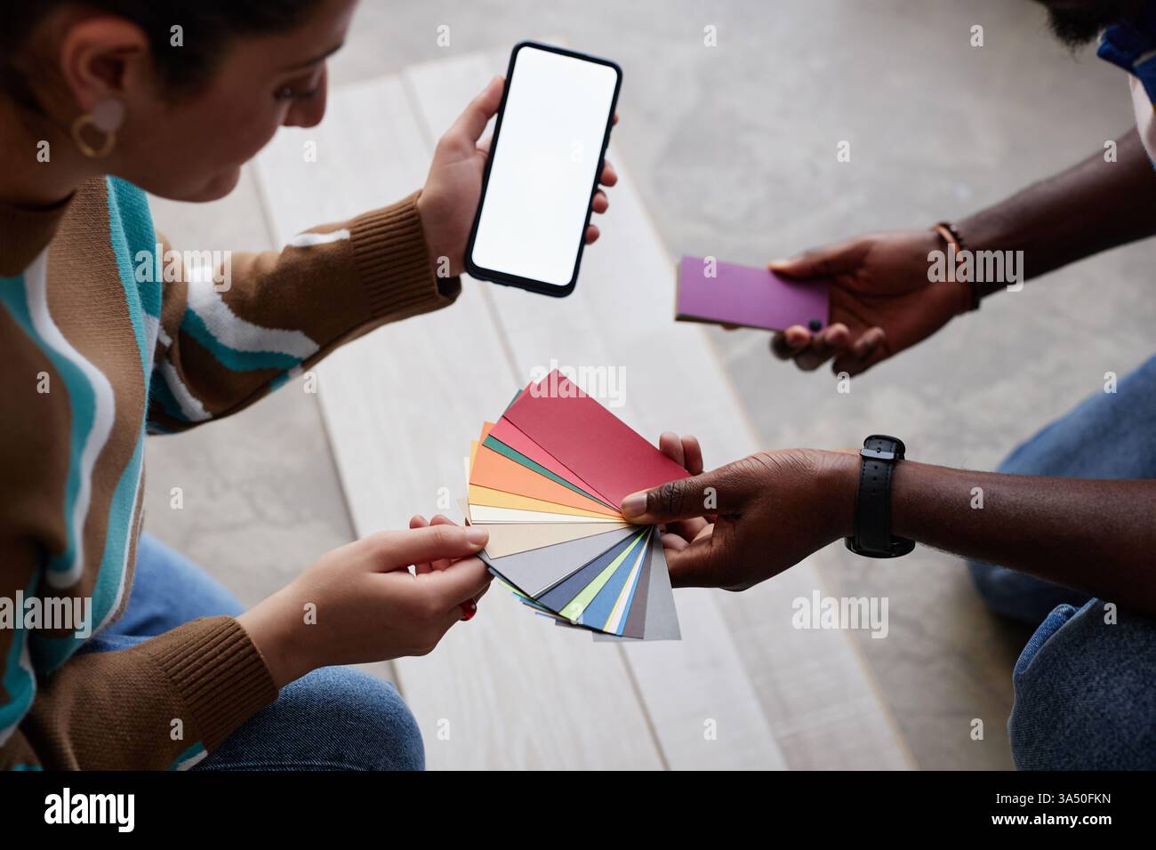 Mixed-race female designer with smartphone choosing color palette held ...