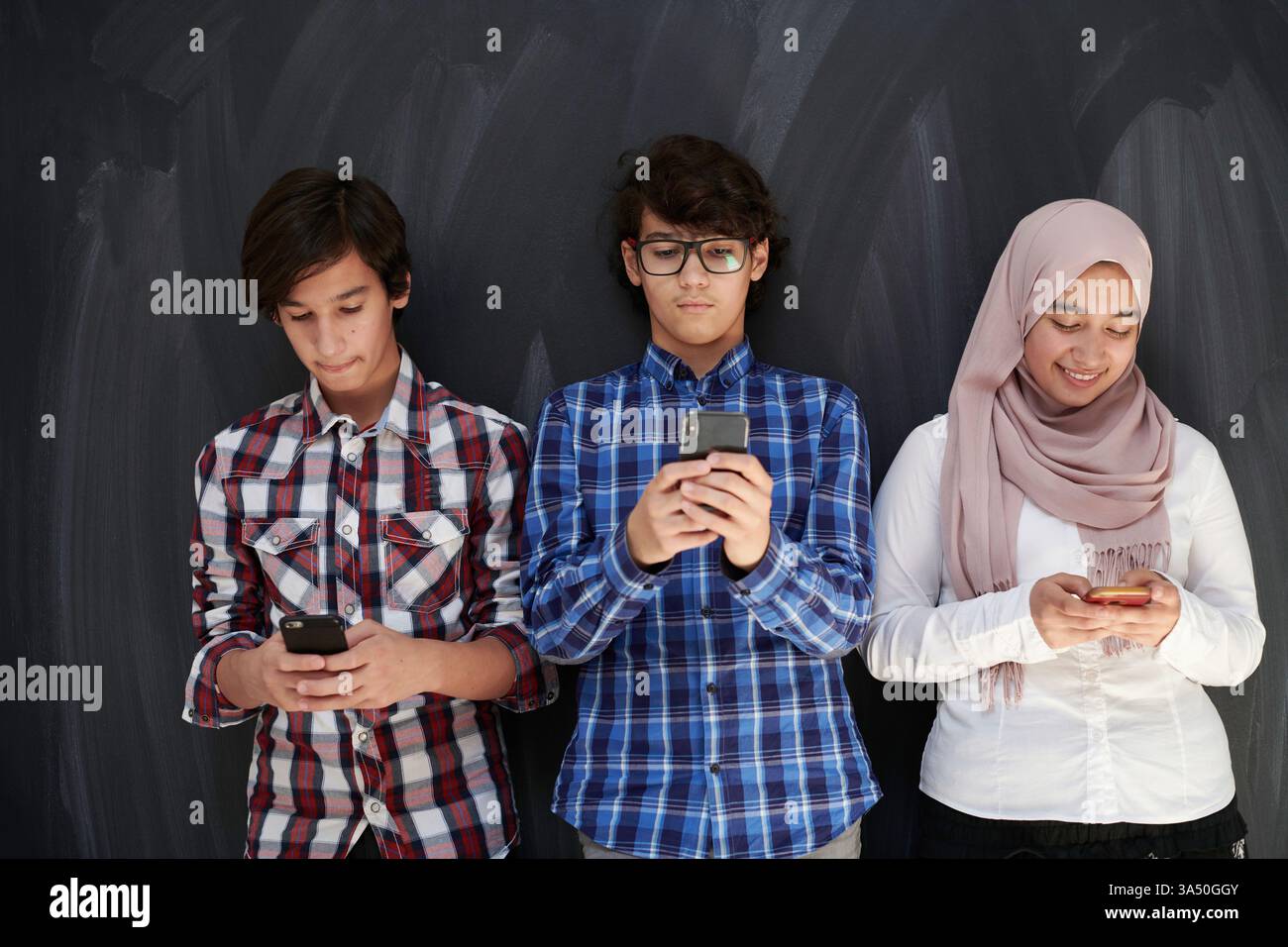 Smiling Muslim woman in a hijab with Middle Eastern male teens using ...