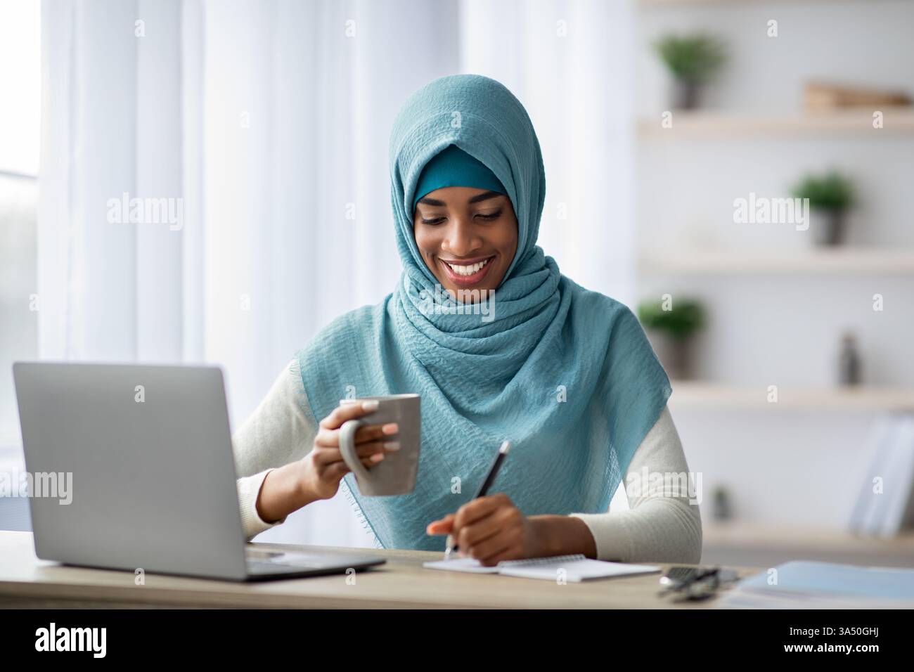 Home Office. Portrait of smiling black muslim freelancer lady drinking ...