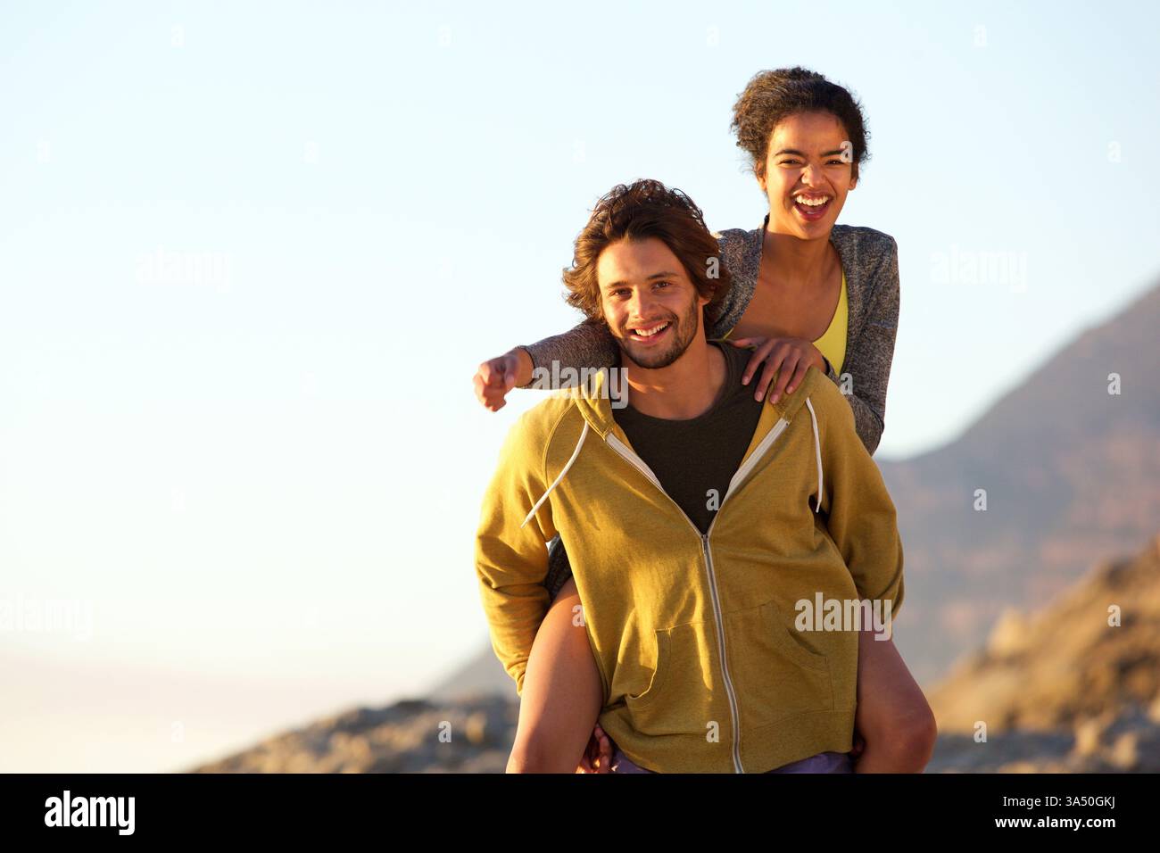 Cheerful Black woman piggyback riding on caucasian boyfriend outdoors ...