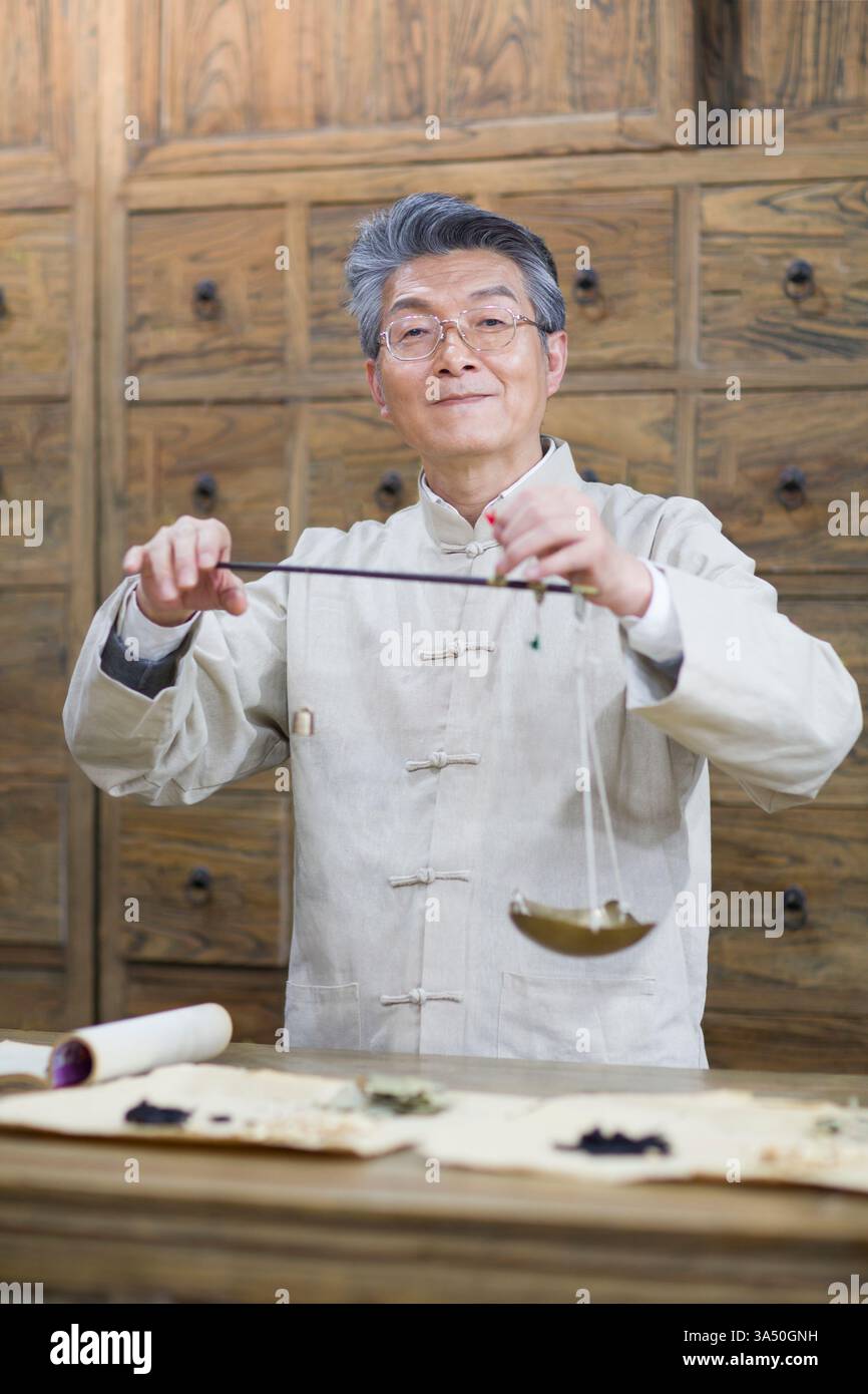 Senior Chinese doctor fills the prescription in a traditional Chinese ...