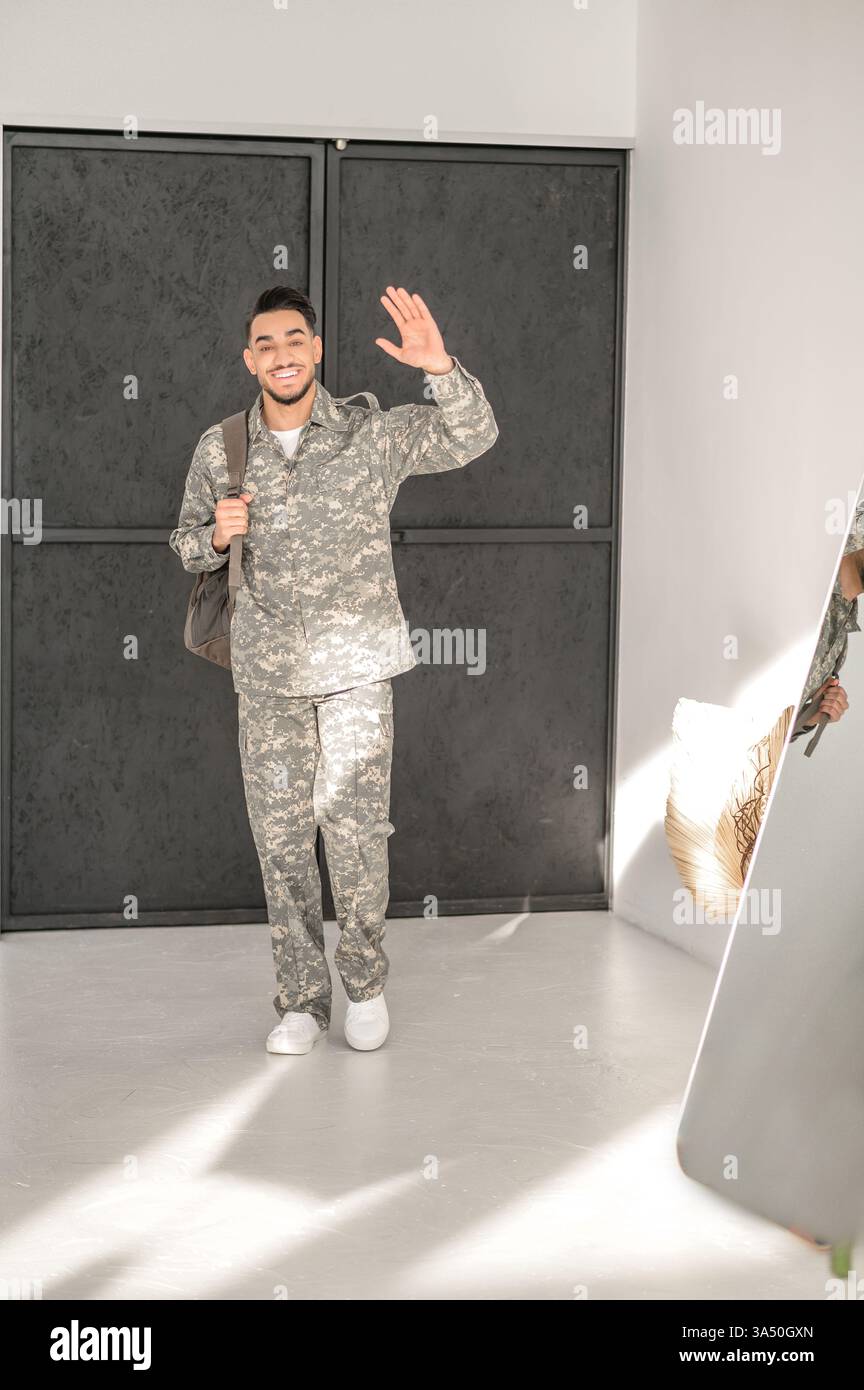 Smiling Arab military man in camouflage uniform greeting at a home ...