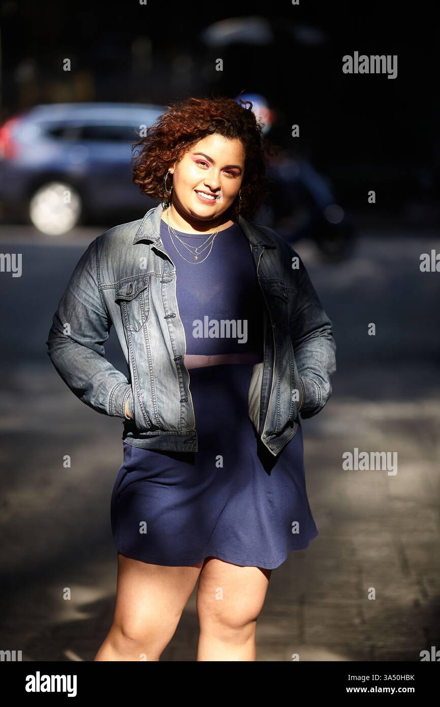 Plus sized Mexican woman standing on street hands on pocket smiling ...