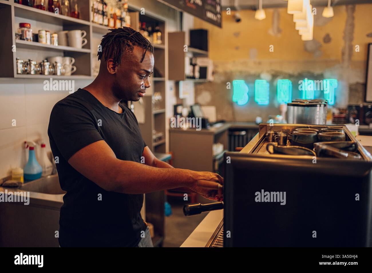 Portrait of an Black male barista behind the counter in a cafe using ...