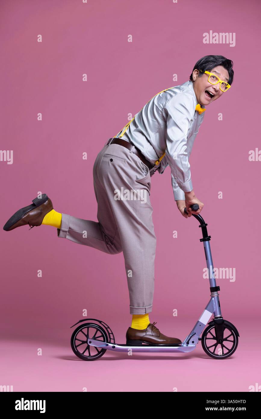 Cheerful senior Chinese man riding scooter Stock Photo - Alamy