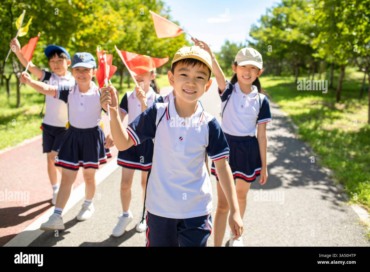 Smiling Chinese boy with classmates in school uniforms wearing hats ...