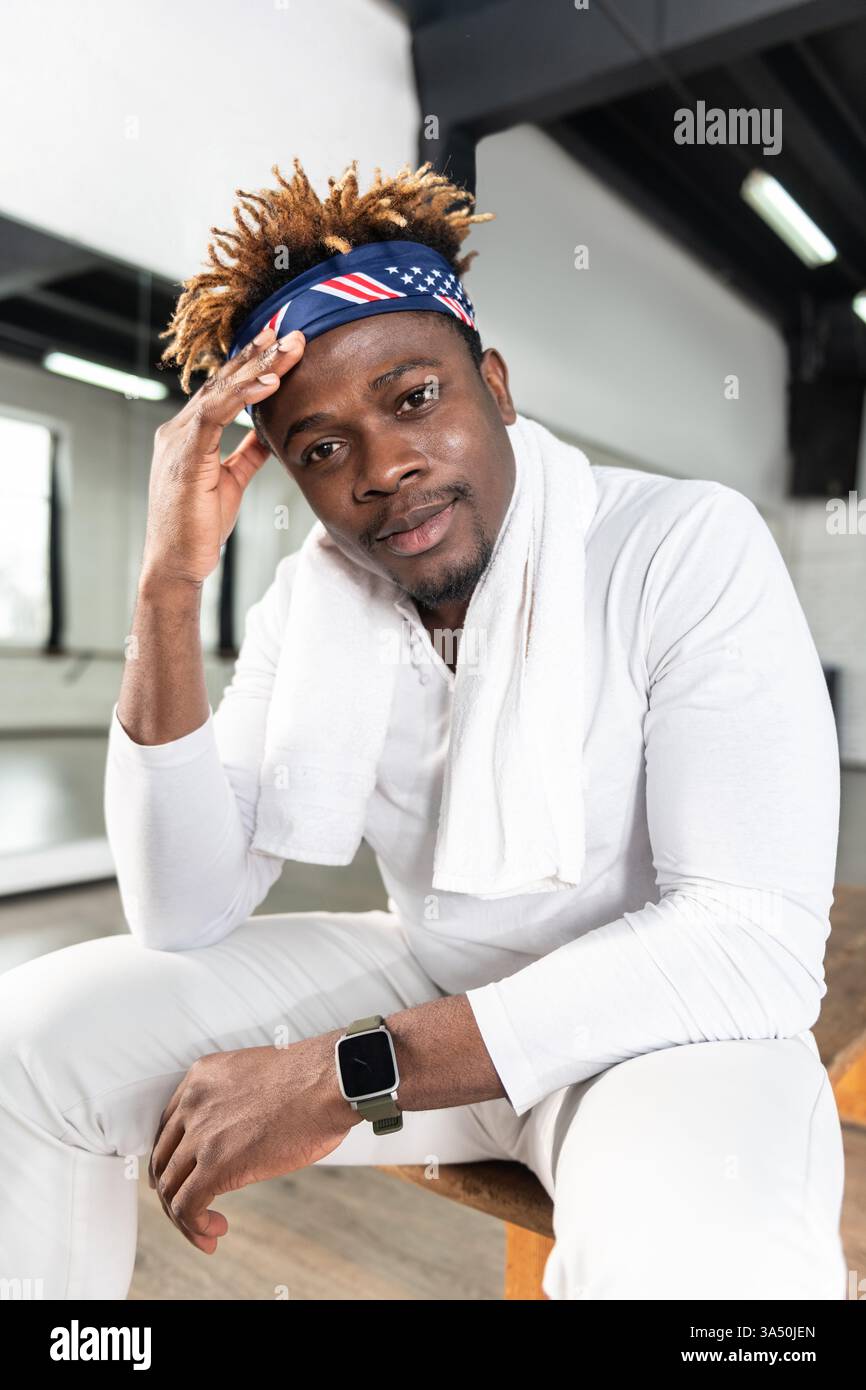 Black male leaning face on hand sitting on bench in dance studio Stock ...