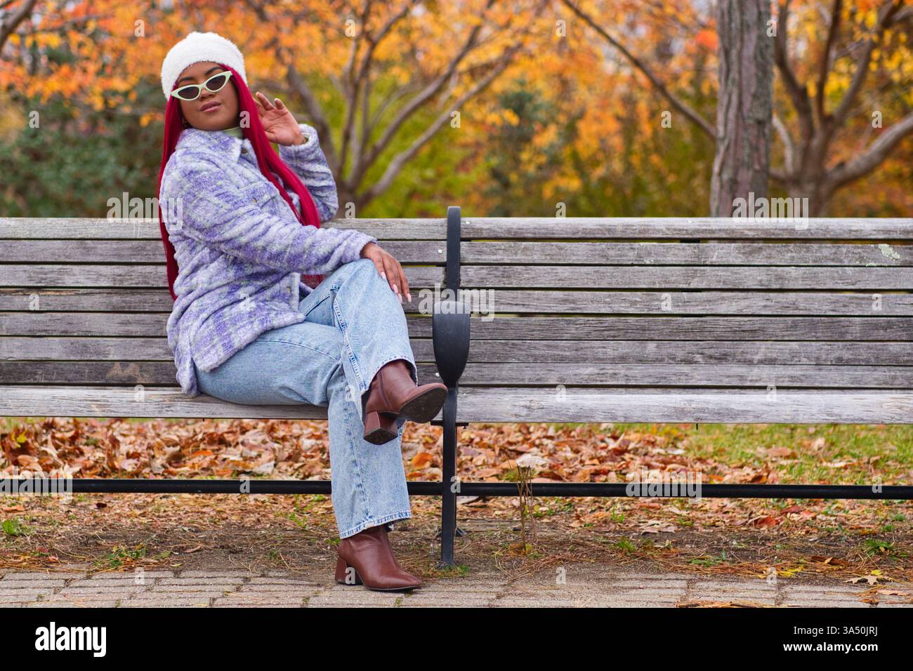 Serious-looking Hispanic woman sits on a wooden bench in a park during ...