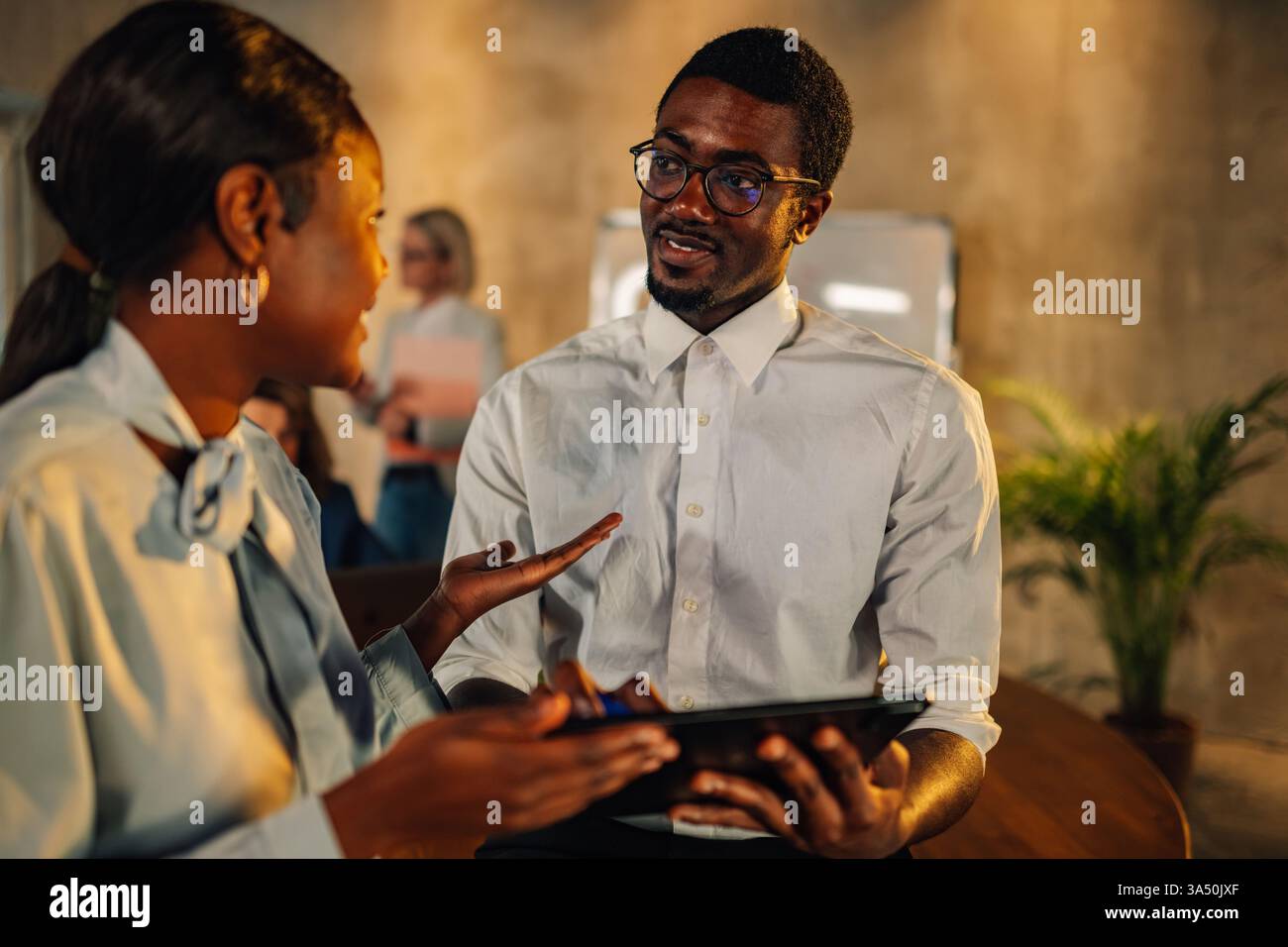 Black businessman holding tablet discussing and showing project plan to ...