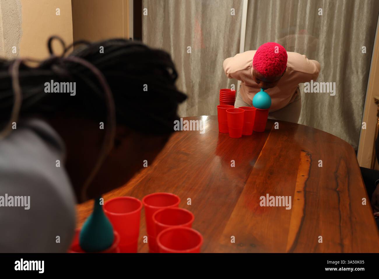 Focused Black female siblings playing balloon cup stacking standing ...