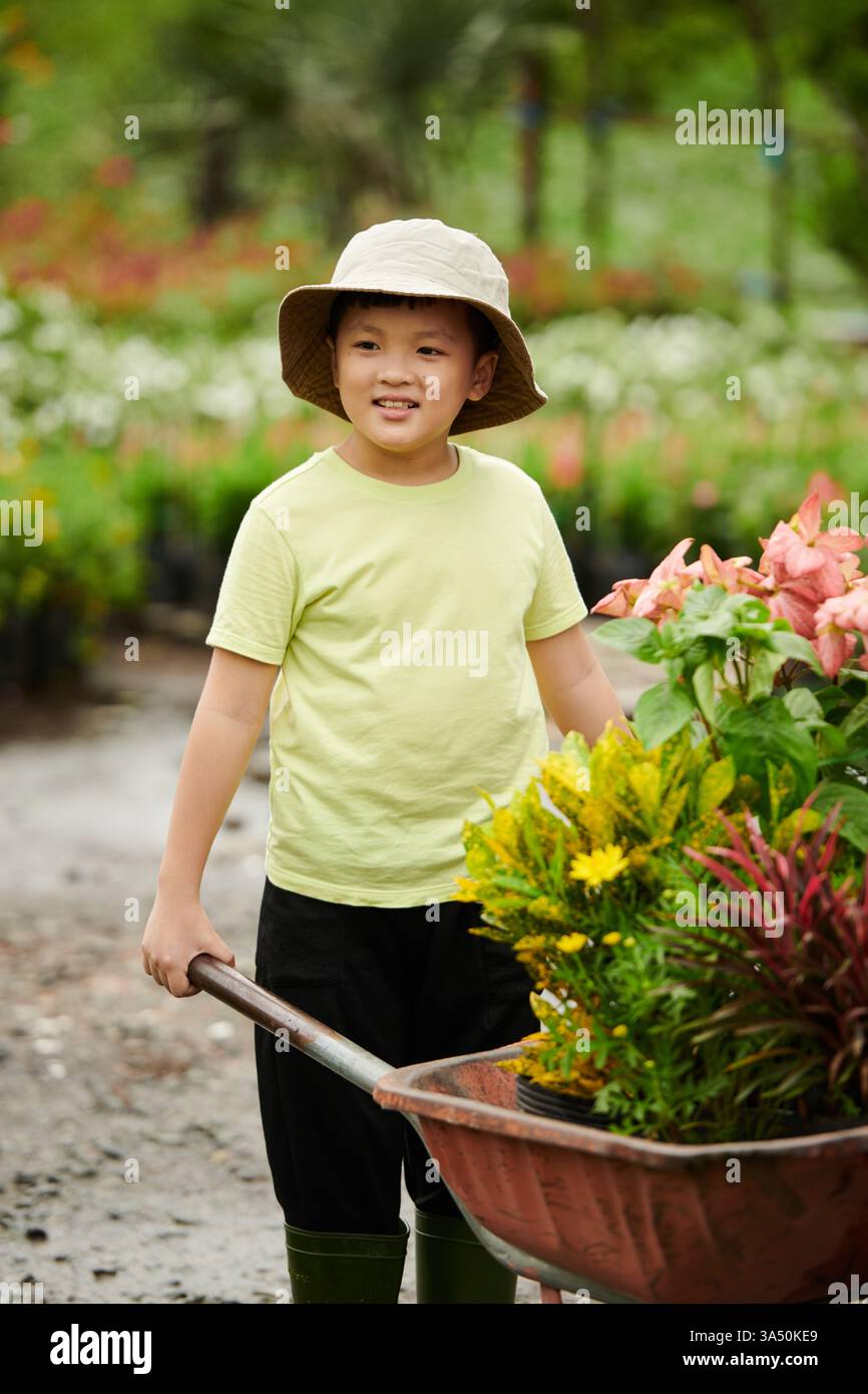 Preteen Asian boy working at flower nursery of his family Stock Photo ...