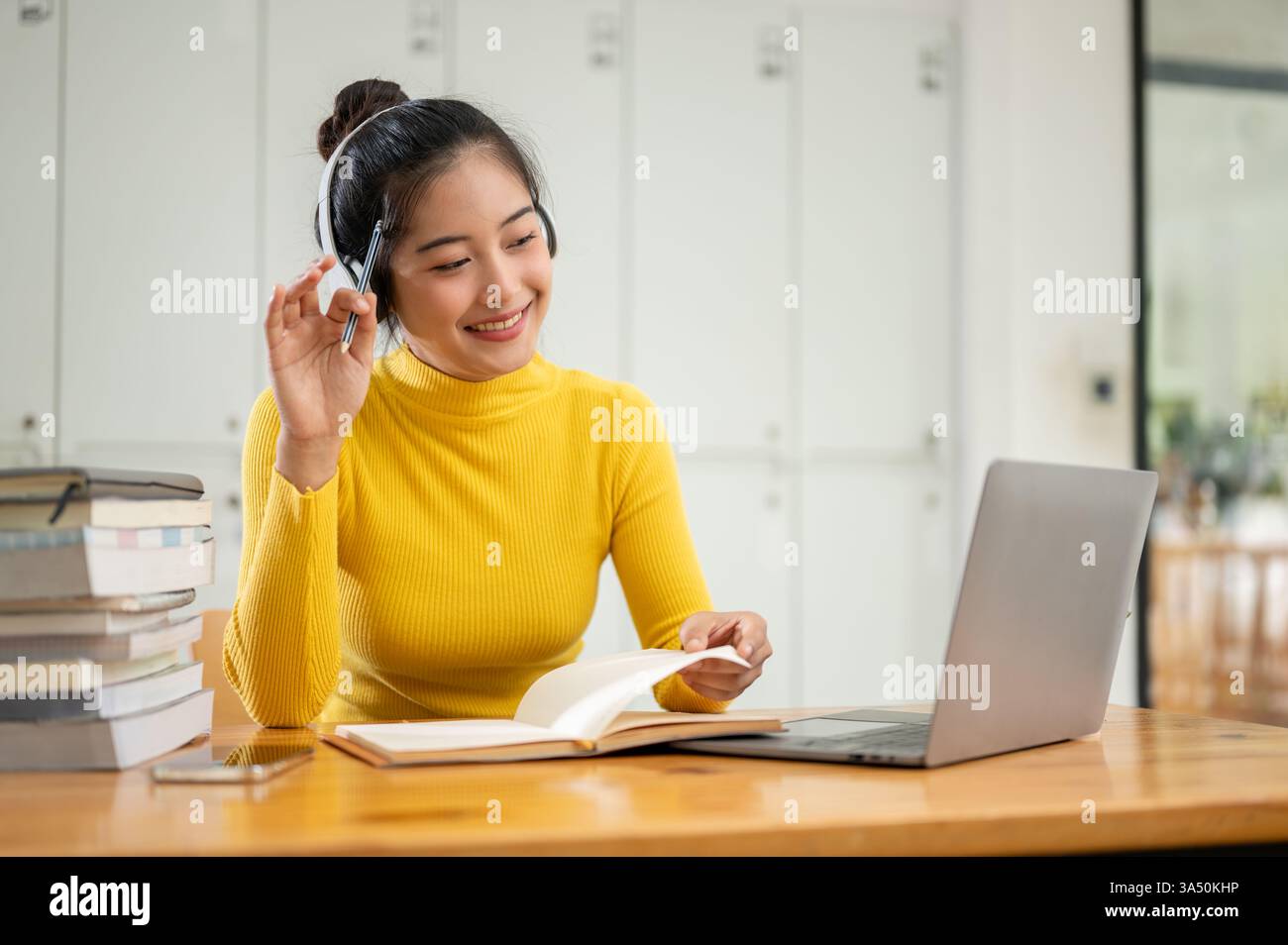 A happy and charming young Asian female university student is studying ...