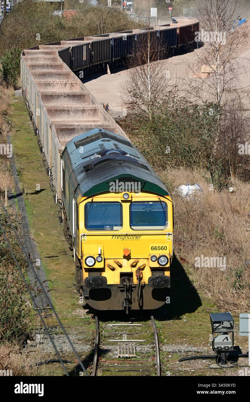 Class 66 diesel with wagons of aggregate being unloaded in the yard at Hitchin, Hertfordshire ...