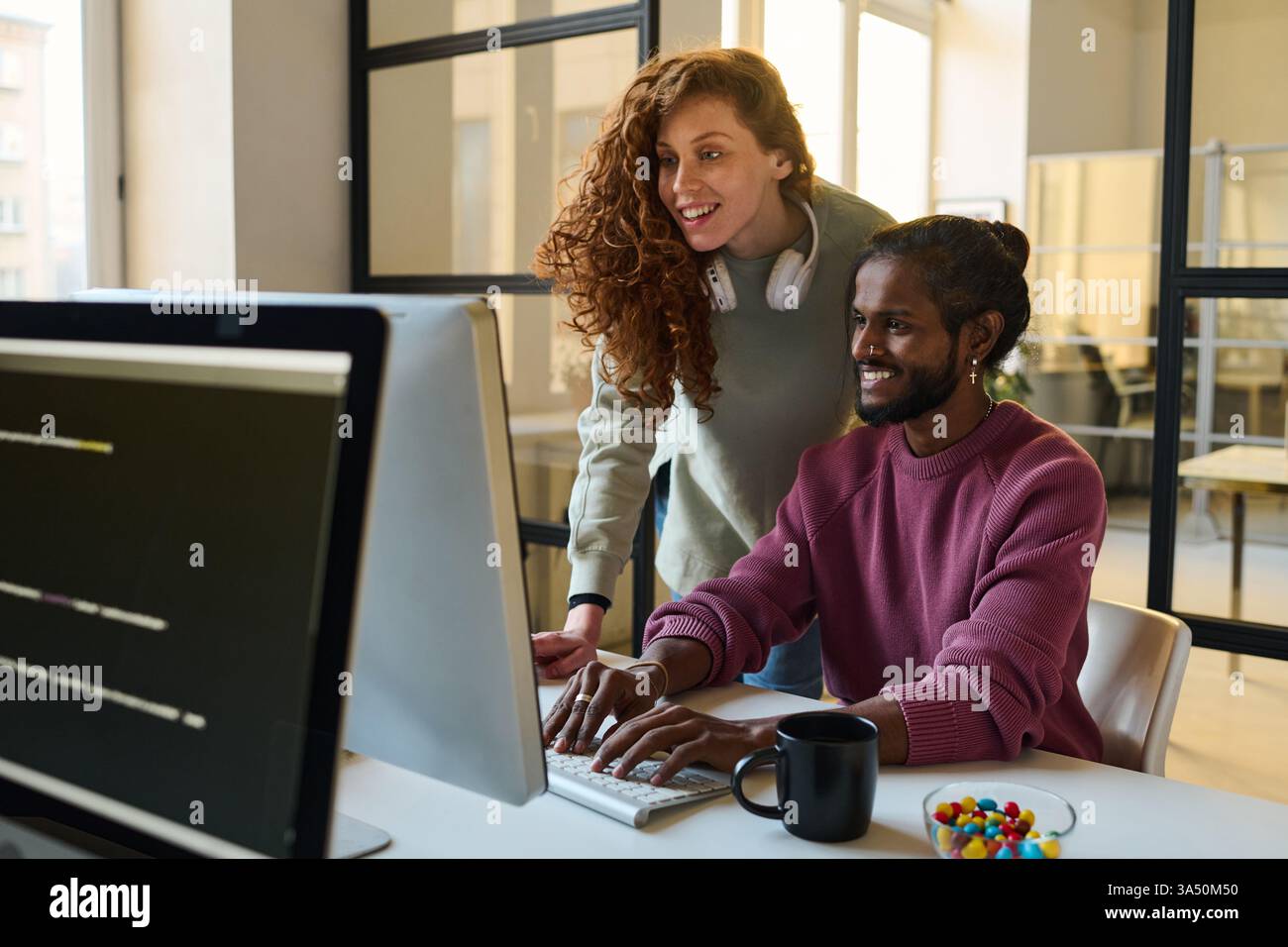 Indian male programmer sitting and working on computer near caucasian ...
