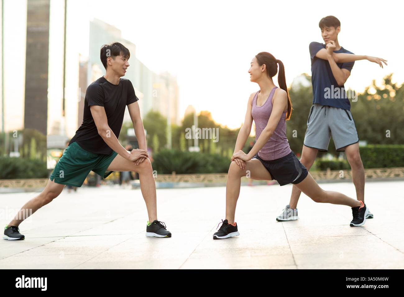 Chinese friends doing stretching exercise while standing on street ...