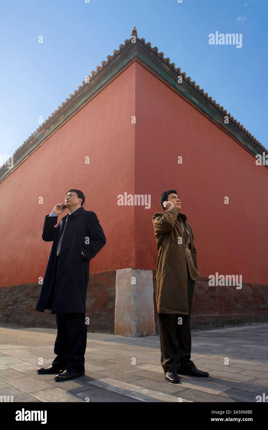 Chinese businessmen looking away having phone conversation standing on ...