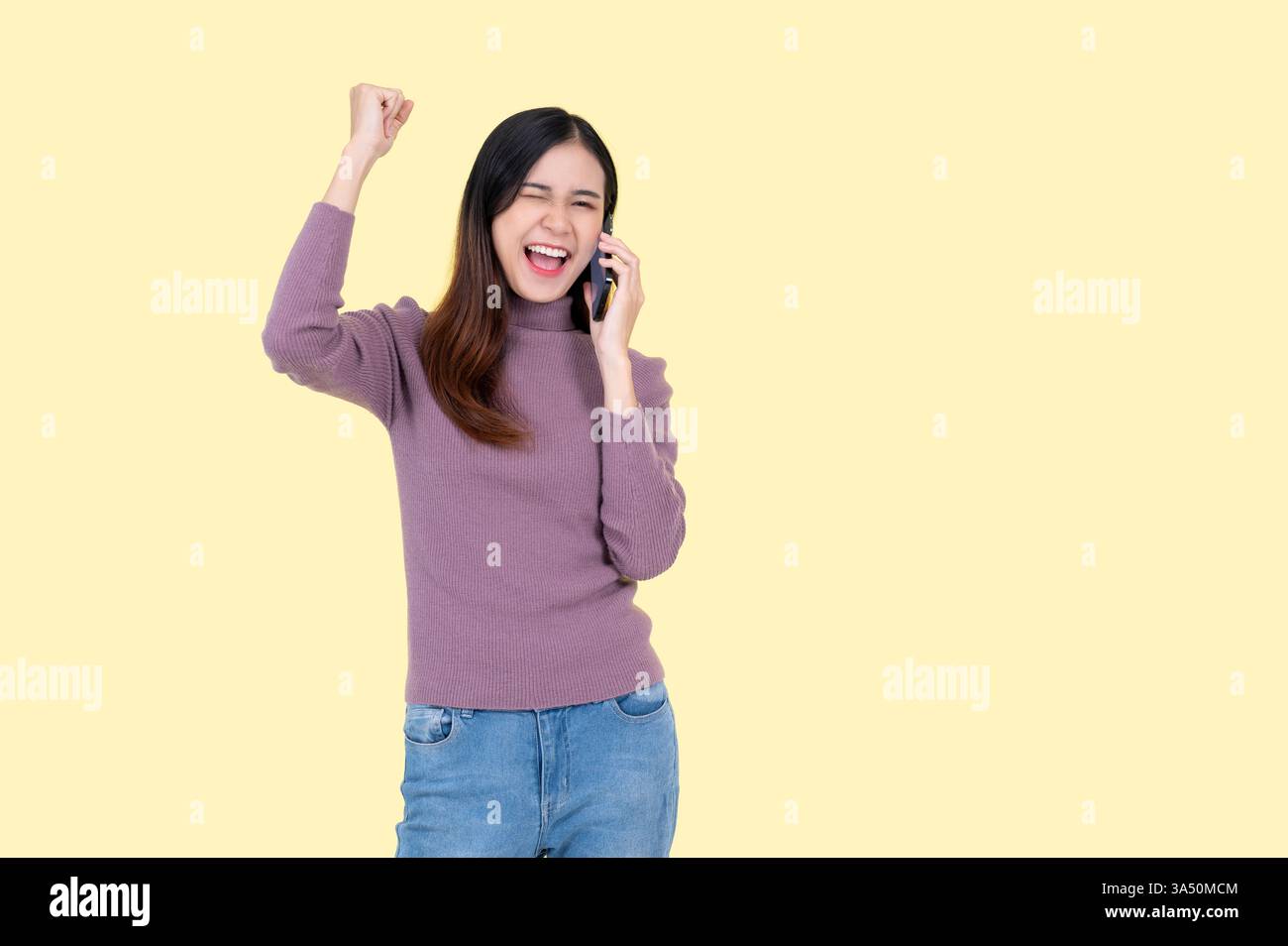 A cheerful and pretty Asian woman is talking on her phone, making a ...