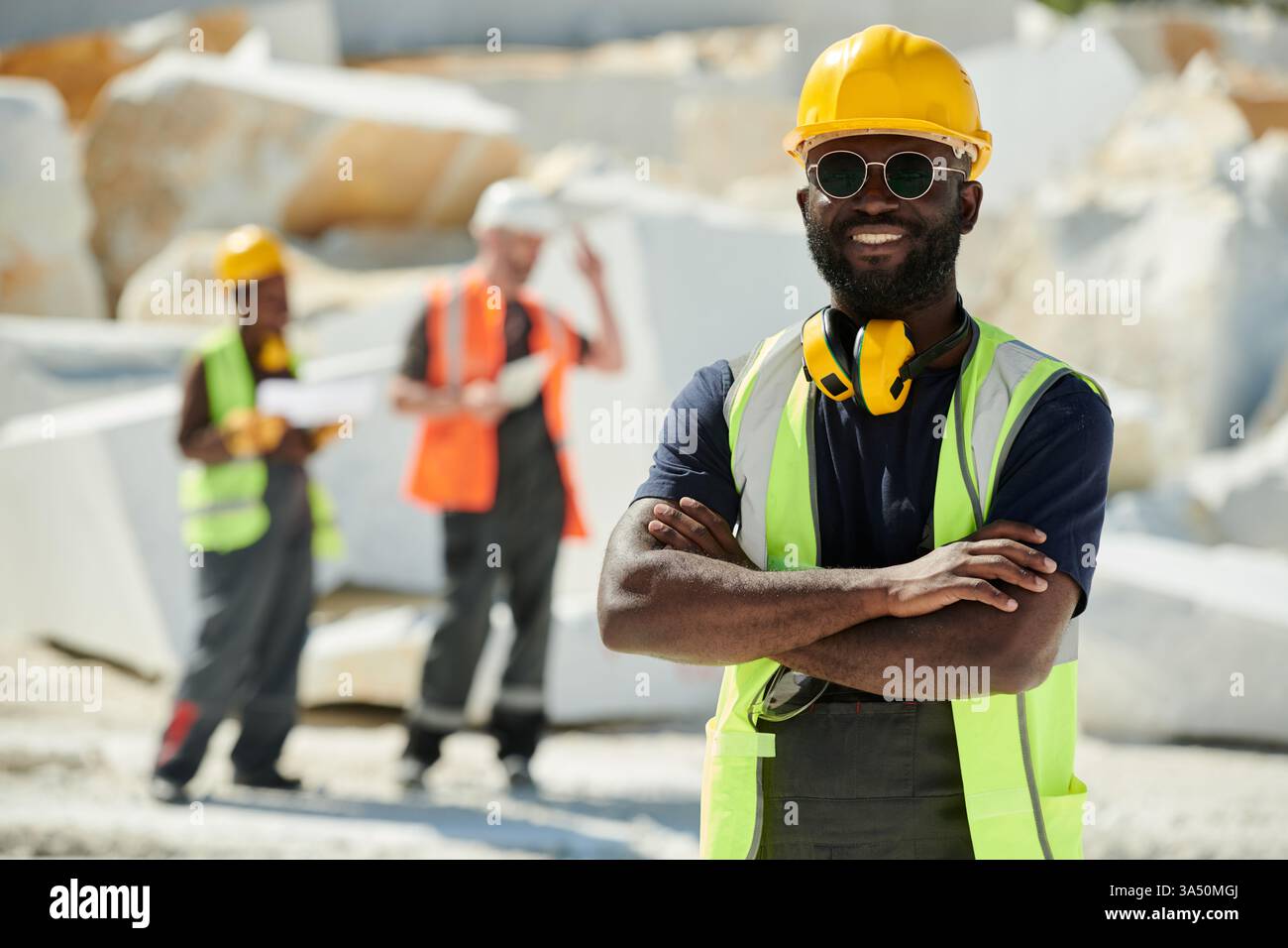 Black male engineer wearing safety helmet and sunglasses standing with ...