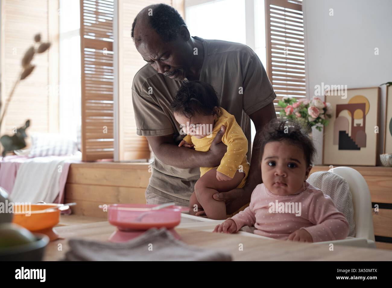Caring African American father helping his twin babies to take seat in ...